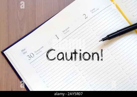 Caution write on notebook Stock Photo - Alamy