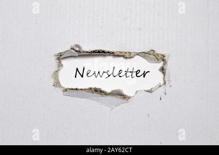 Newsletter concept text appearing behind torn brown paper envelope ...