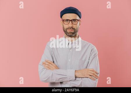 Headshot of handsome unshaven man wears transparent glasses, headgear ...