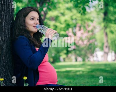 A young woman drinks water from a public outdoor drinking fountain ...
