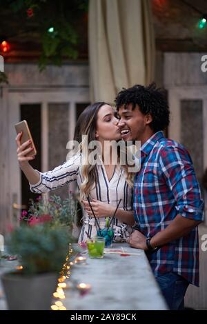 Smiling multiethnic couple taking selfie on smartphone on ice rink ...