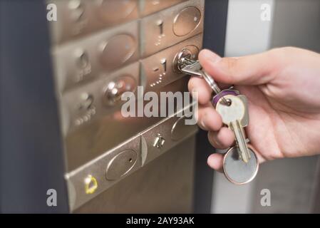 Elevator access control. hand holding a key to unlock elevator floor ...