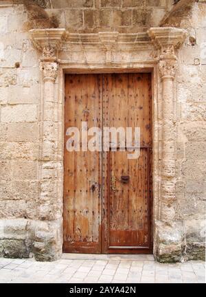 Rustic wooden door with iron studs in stone historical building facade ...