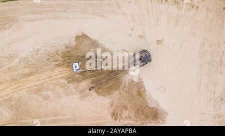 Aerial top down view of an excavator loading earth into a dump truck in ...