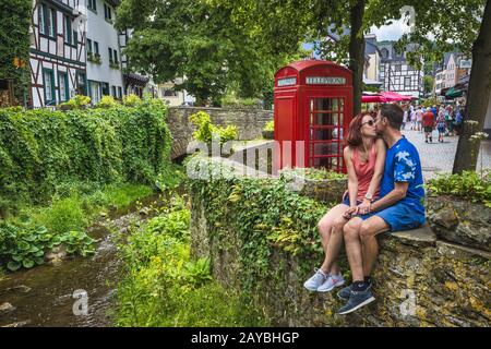 Couple sitting on wall kissing Stock Photo - Alamy