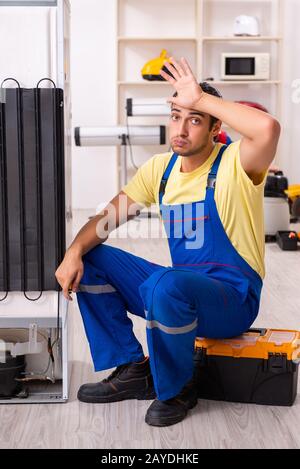 The two contractors repairing fridge at workshop Stock Photo - Alamy