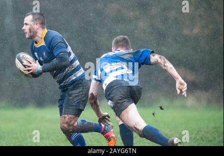 Muddy rugby player running in mud with ball. competition winning sports ...