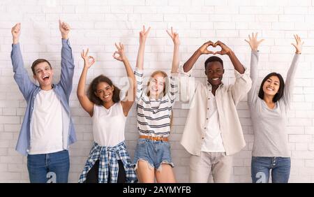 Lifeful young friends putting hands up, showing diverse gestures Stock ...
