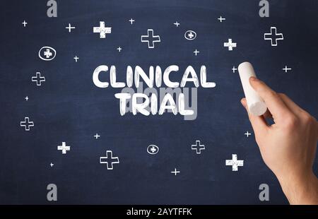 Hand drawing CLINICAL TRIAL inscription with white chalk on blackboard ...