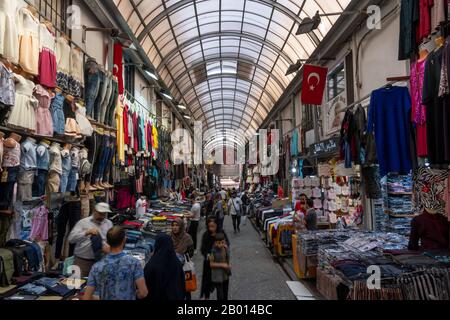 People shopping at a Turkish market with clothes and fabrics on display ...