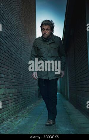 Suspicious man walking in dark urban alley Stock Photo - Alamy