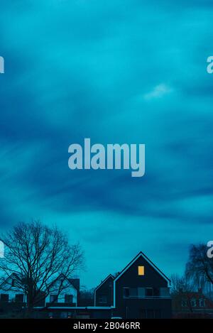 Creepy house with illuminated windows under stormy sky at twilight ...