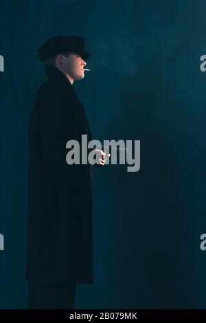 Retro mobster with cigarette shoots with gun. Side view Stock Photo - Alamy