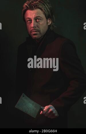 Threatening man with cleaver in hand illuminated by red and blue light ...