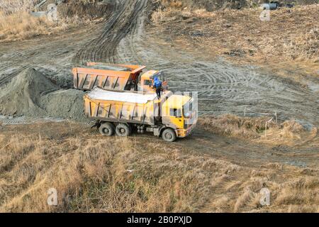 Dump truck unloading process. Dumper trucks unloading earth material or ...