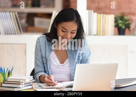 Asian student with laptop preparing for exam at home Stock Photo - Alamy