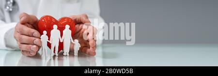 Close-up Of A Doctor's Hand Protecting Family Cut Out With Red Heart ...