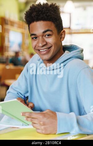 Smiling african boy teenager studying while sitting at the hub indoors ...