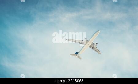 Commercial passenger airplane viewed from below against a blue sky with ...