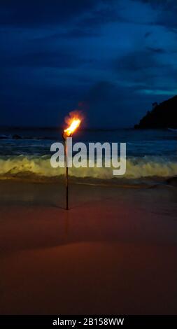 Burning torch on the sandy beach of the ocean Stock Photo - Alamy
