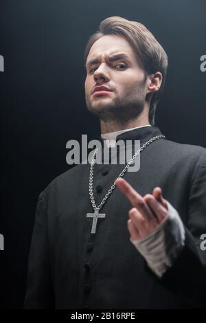 displeased catholic priest showing middle finger while looking at ...
