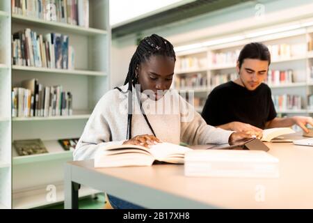 Two students learning together indoors in library Stock Photo - Alamy