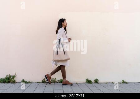 Young woman walking along wall holding boyfriend's hand for balance ...