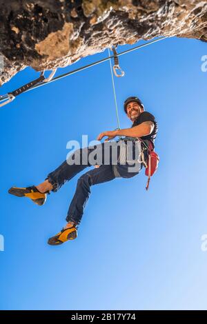 Smiling climber abseiling from rock face Stock Photo - Alamy