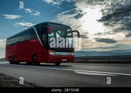 Red Modern comfortable tourist bus driving through highway at bright ...