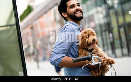 Image of handsome young man, pet owner standing with his dog and ...