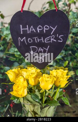 Happy Mothers Day message written on paper heart with flowers on brown ...