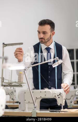Young man sewing on buttons on sleeve of shirt at home table Stock ...