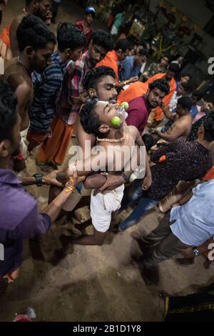 Devotees having a spear piercing in his mouth (Kavadi Aattam) as an act ...