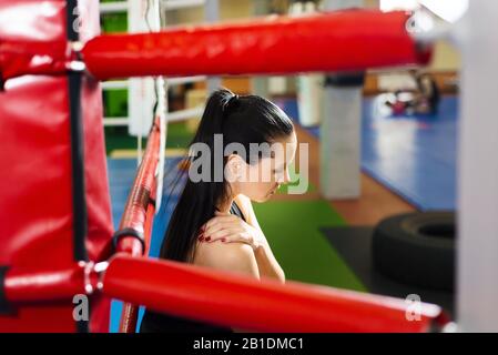 Portrait of tired female boxer sitting on stool at corner in boxing ...
