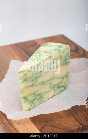 A wedge of Sage Derby cheese made with cow’s milk that has been ...