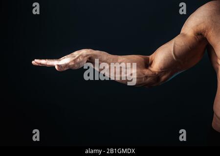 tense arm, veins, bodybuilder muscles on a dark background, isolate ...
