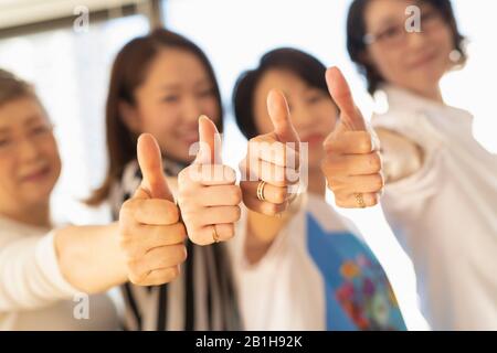 Four women showing thumbs up sign Stock Photo - Alamy