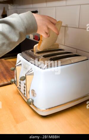 Toaster with toasted bread for breakfast inside. The female hand pulls ...