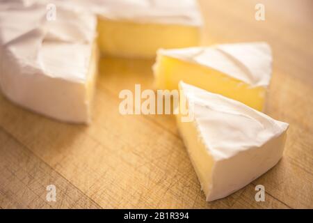 Camembert cheese with two triangles slices on a wooden board Stock ...