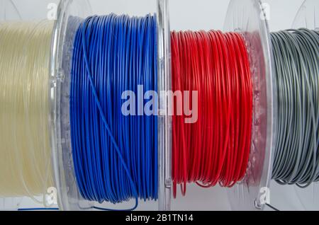 Close up view of coils of plastic for 3D printing. Red, white and blue ...