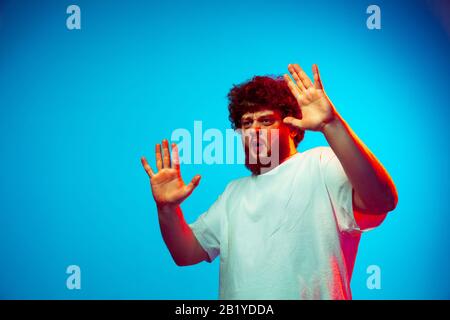 Scared, disguasted. Caucasian man's portrait isolated on blue studio ...