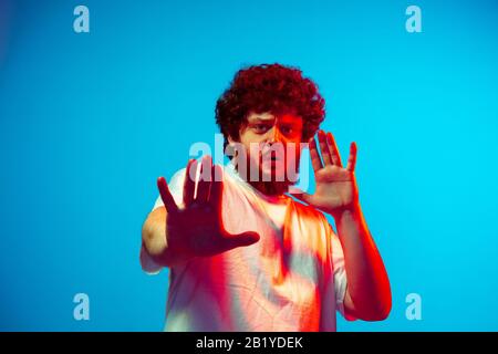 Scared, disguasted. Caucasian man's portrait isolated on blue studio ...