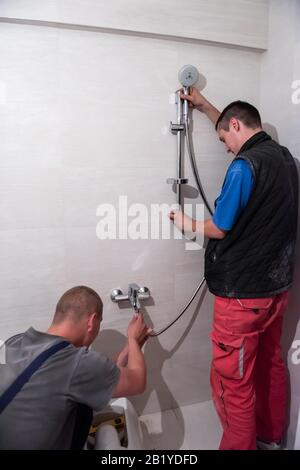 two professional plumbers working together in a bathroom, plumbing ...