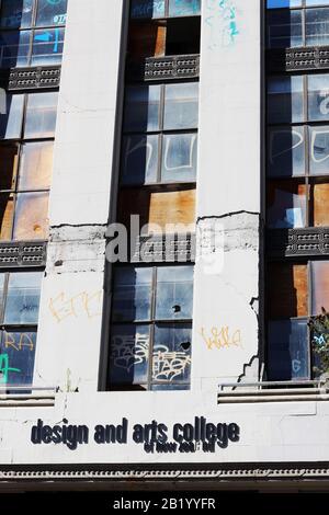 Broken windows and graffiti tags on outside wall of abandoned cement ...