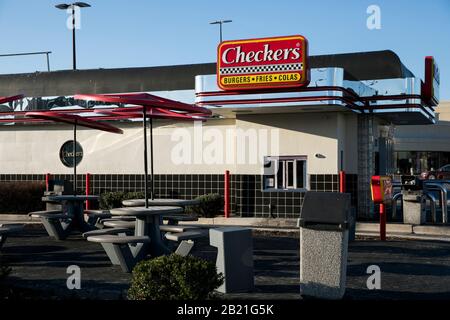 A logo sign outside of a Checkers fast food restaurant location in ...