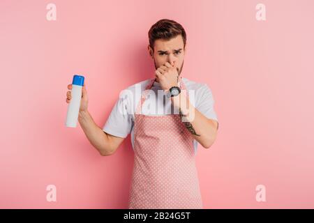 displeased young man plugging nose with hand while holding deodorant ...