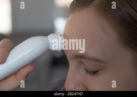Girl using a temporal artery thermometer on her forehead Stock Photo ...