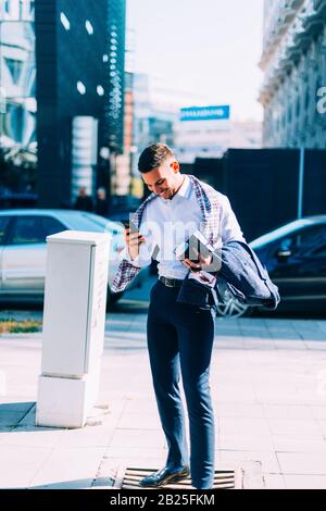 Businessman is standing on the street on a windy day and looking ...