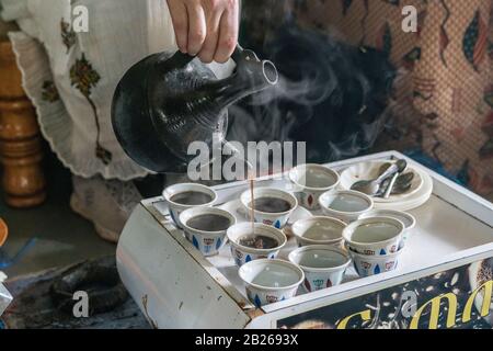 Woman pouring traditionally brewed coffee into finjal - coffee cup ...