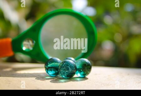 Magnifier on the sunlight with green three marbles on light passing in ...